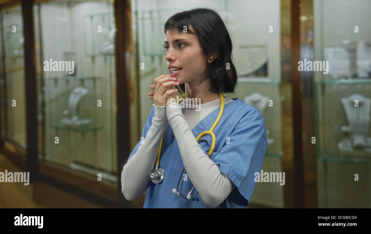 Woman nurse wearing blue scrubs and stethoscope gently clasping her ...