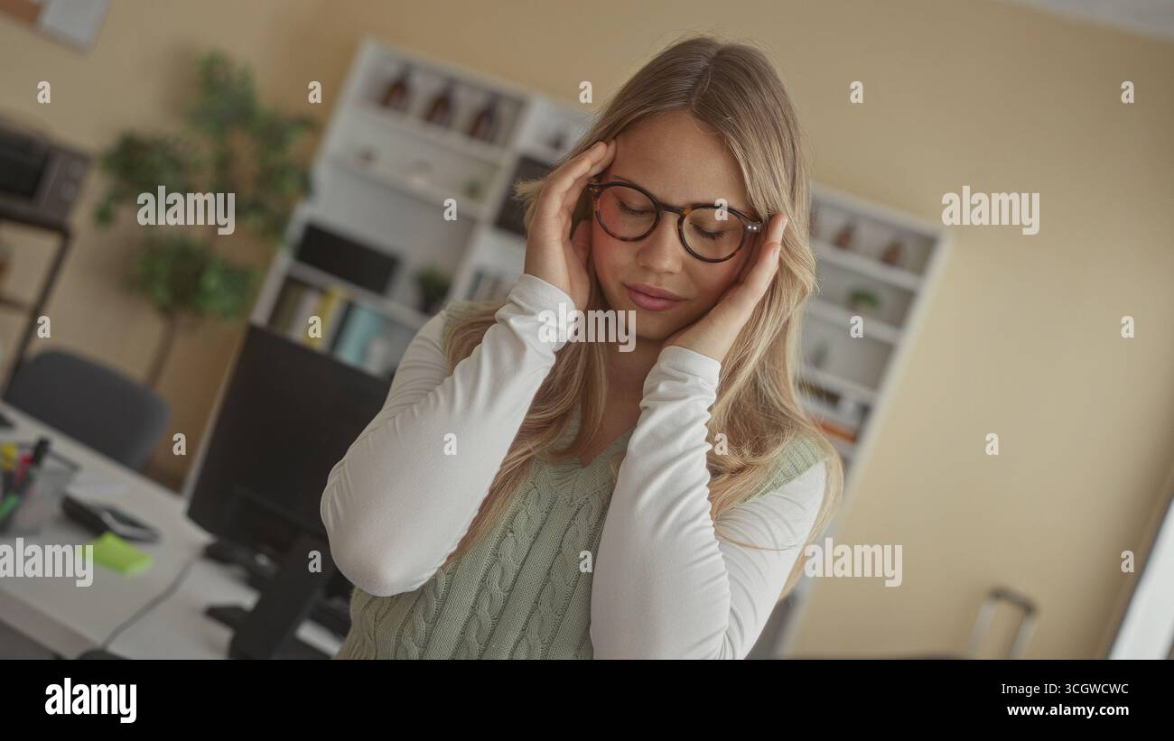 Blonde woman wearing glasses holds head with both hands for dizziness ...