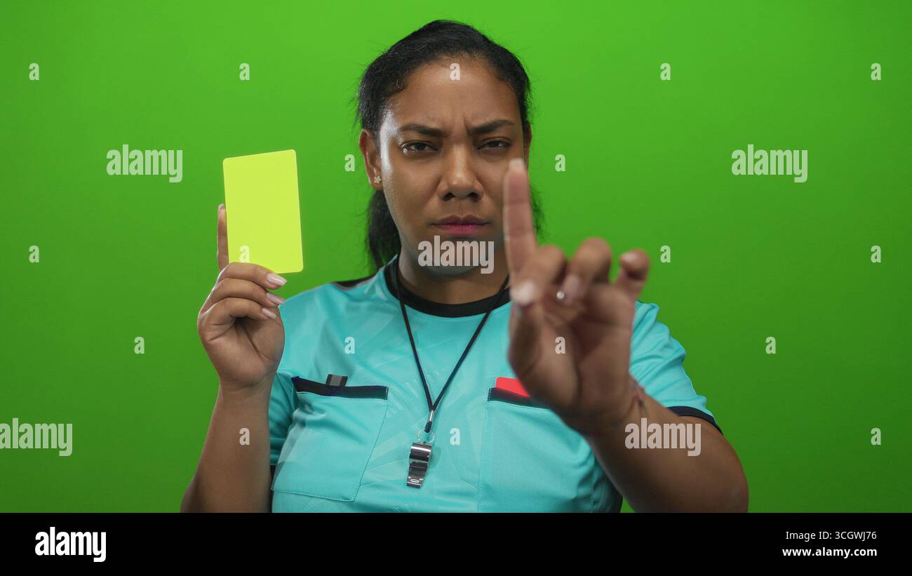Referee holds yellow card toward camera in green studio with serious ...