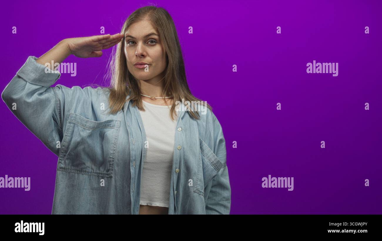 Woman with blonde hair and raised hand salutes in purple studio setting ...