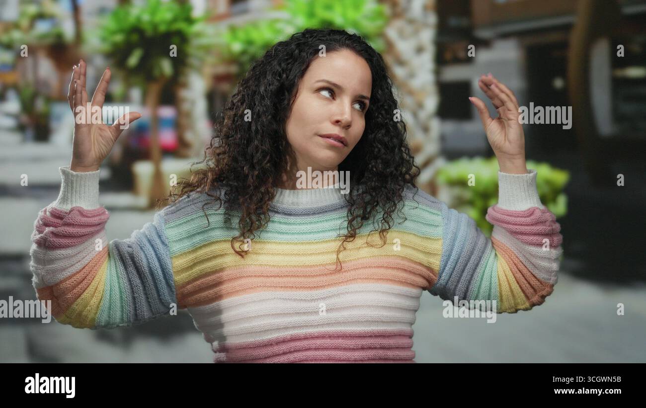 Woman gesturing expressively on a vibrant street wearing a colorful ...
