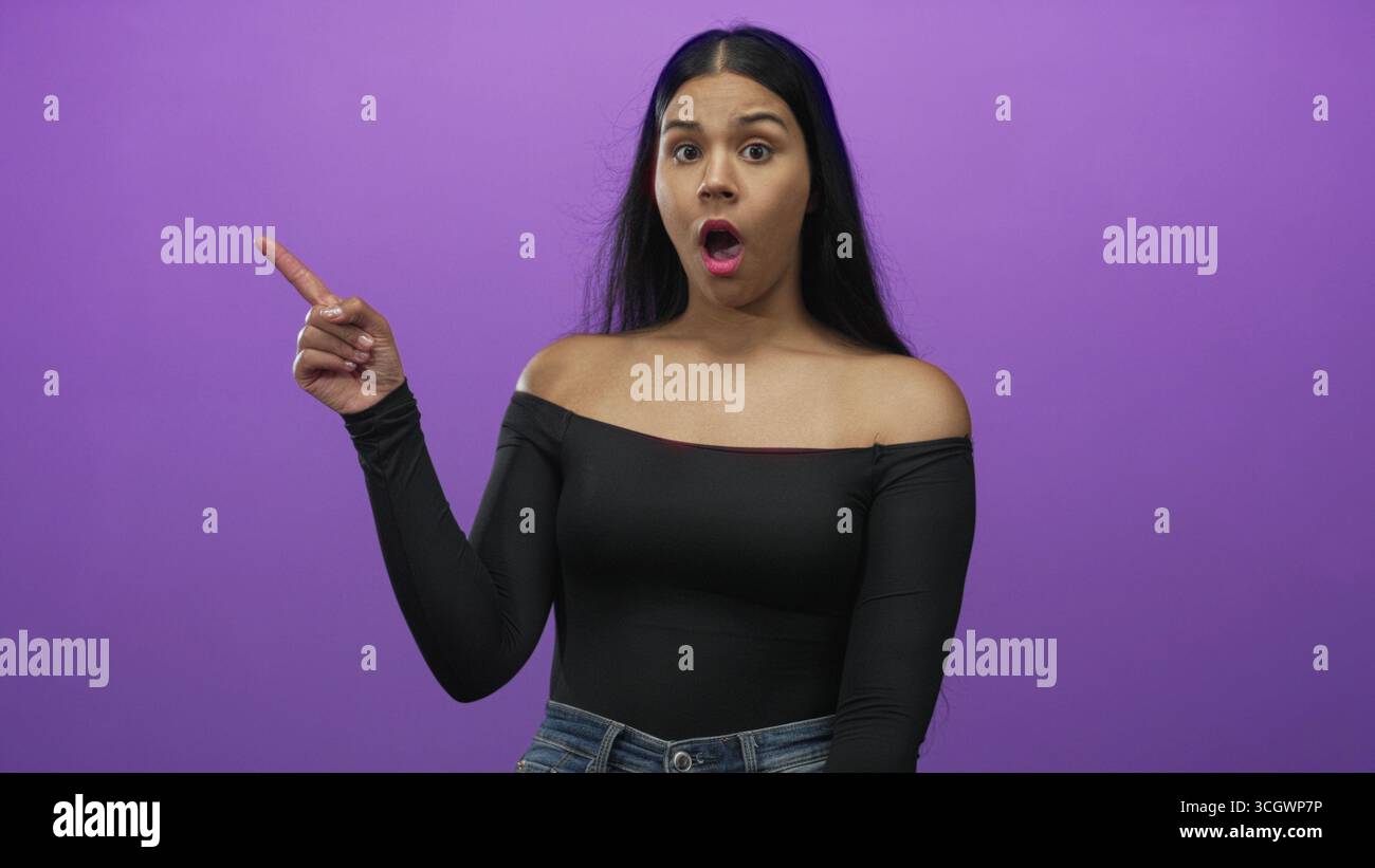 Young latin woman points finger to the side in a studio setting with ...