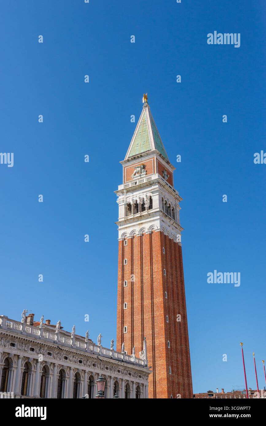 Iconic Venetian tower with red brick and green spire beside historic ...