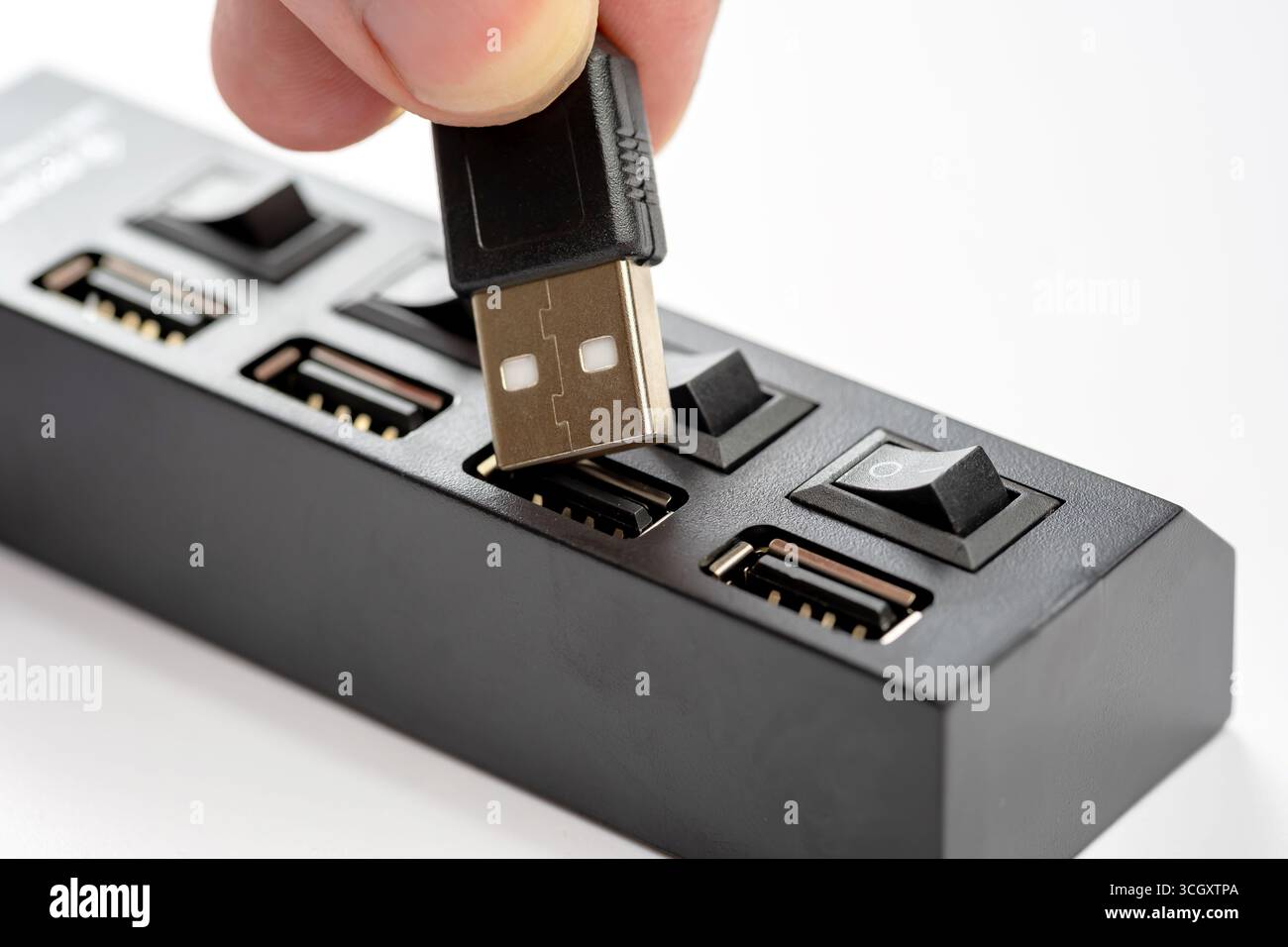 Closeup of a hand plugging in a USB cable into a black multi-port usb ...