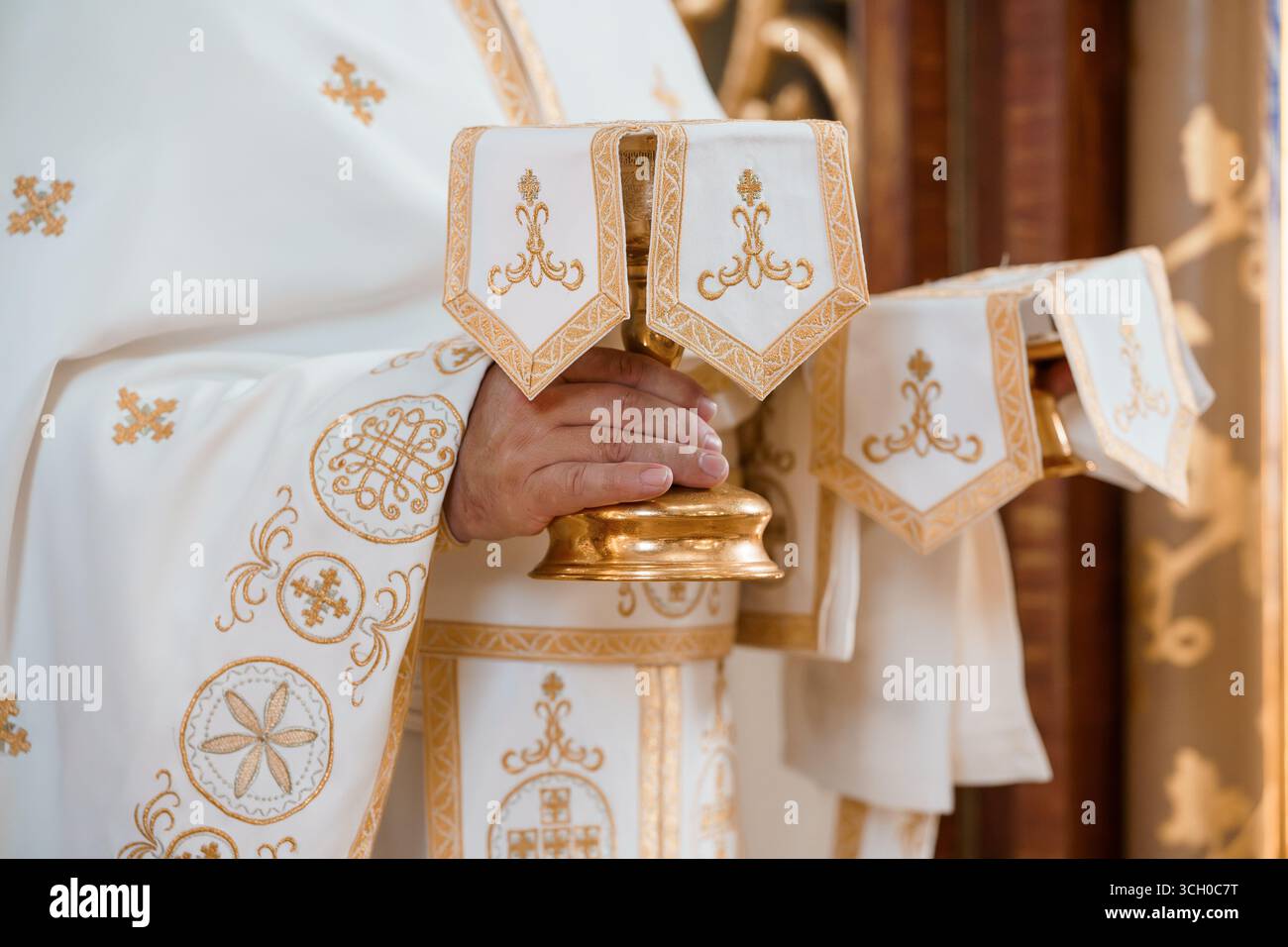Close-up shot of an Eastern Orthodox priest presenting a golden chalice ...
