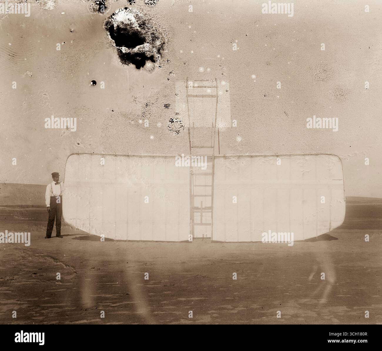 Orville at left wing end of upended glider, bottom view; Kitty Hawk ...