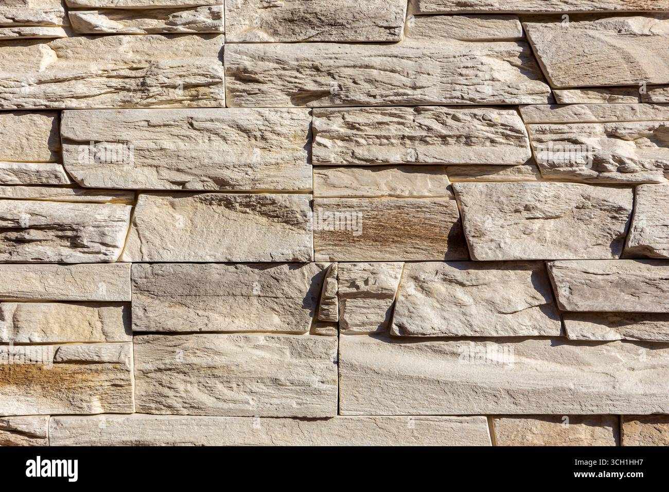 Light stone veneer cladding, decorative brick facing on a residential building facade in beige ...