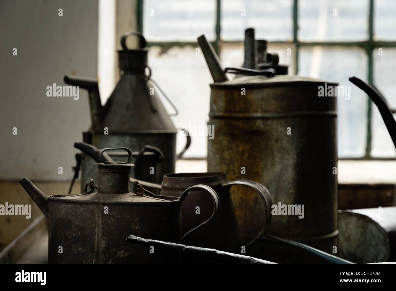 Old metal oil cans and jugs on a workbench in an industrial workshop ...
