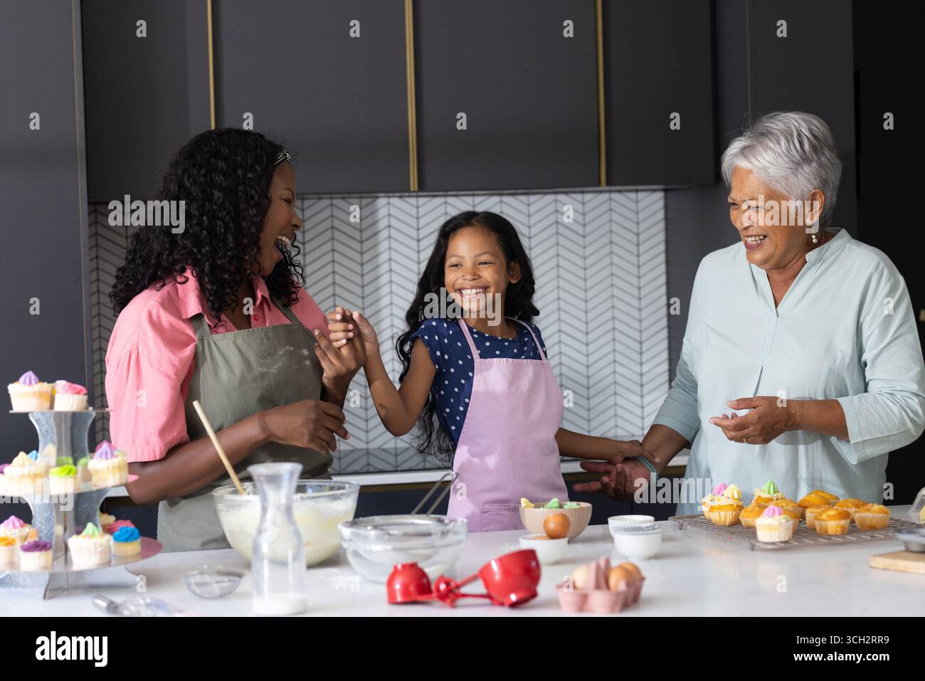 Three generations of women baking cupcakes together, sharing laughter ...