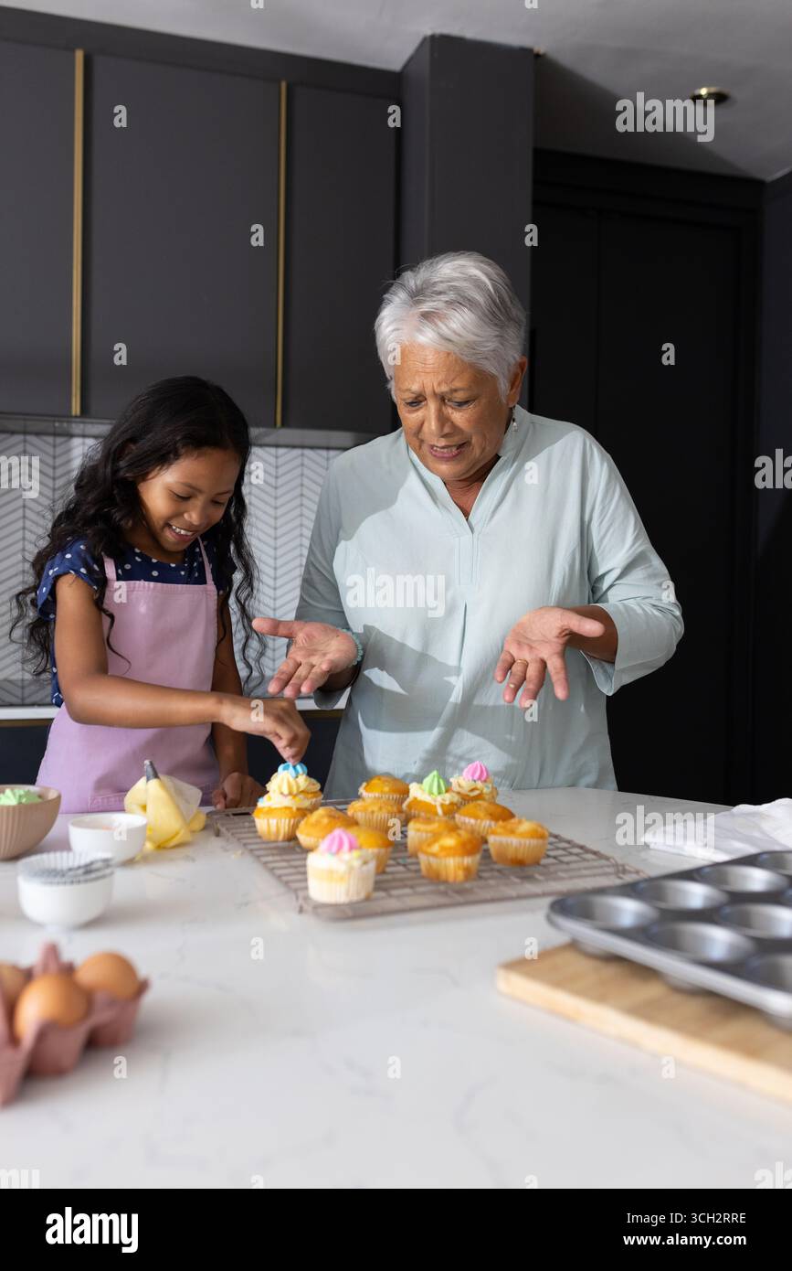 Decorating cupcakes, grandmother and granddaughter sharing laughter in ...