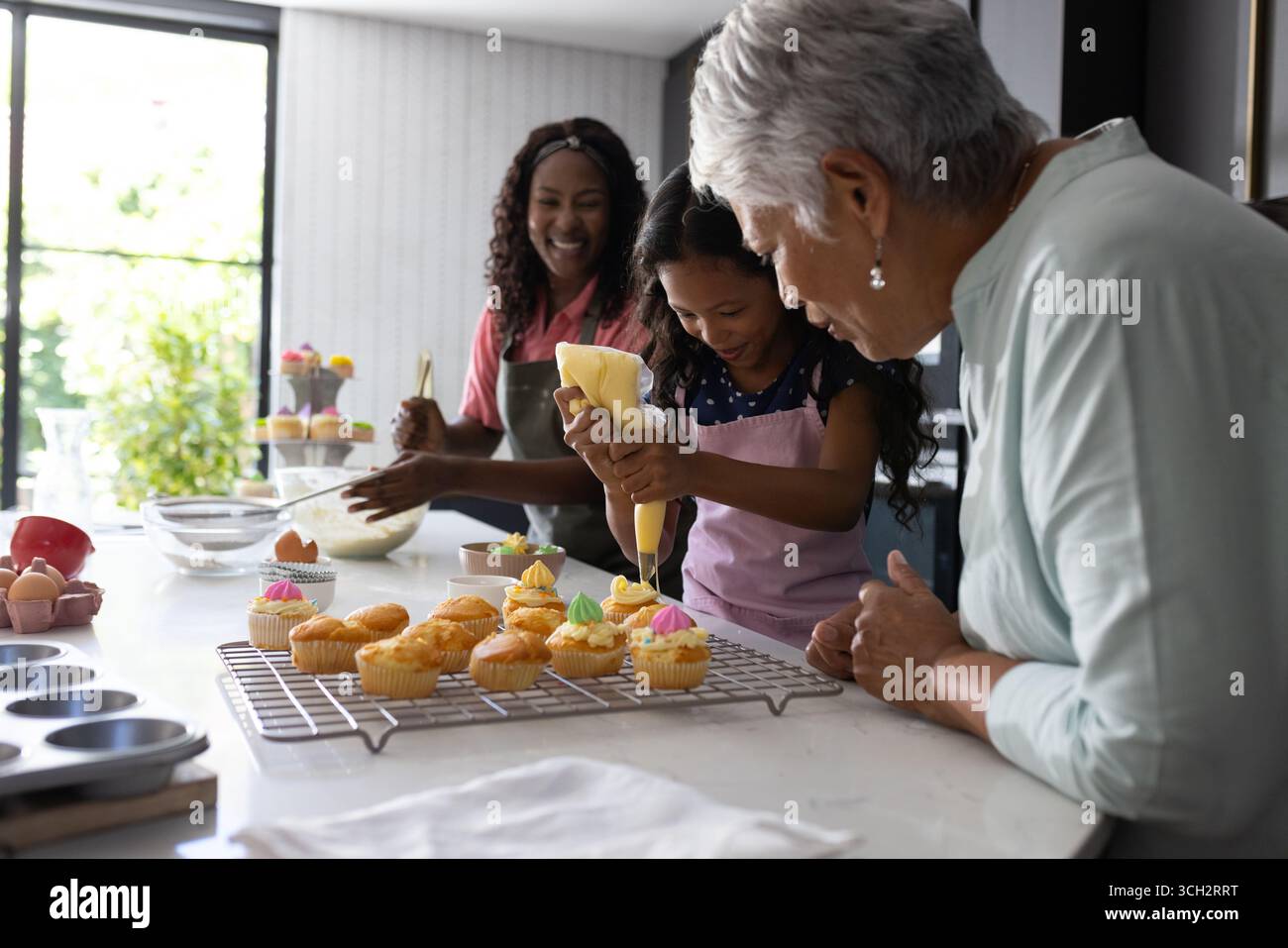 Baking cupcakes, three generations decorating with icing, sharing ...