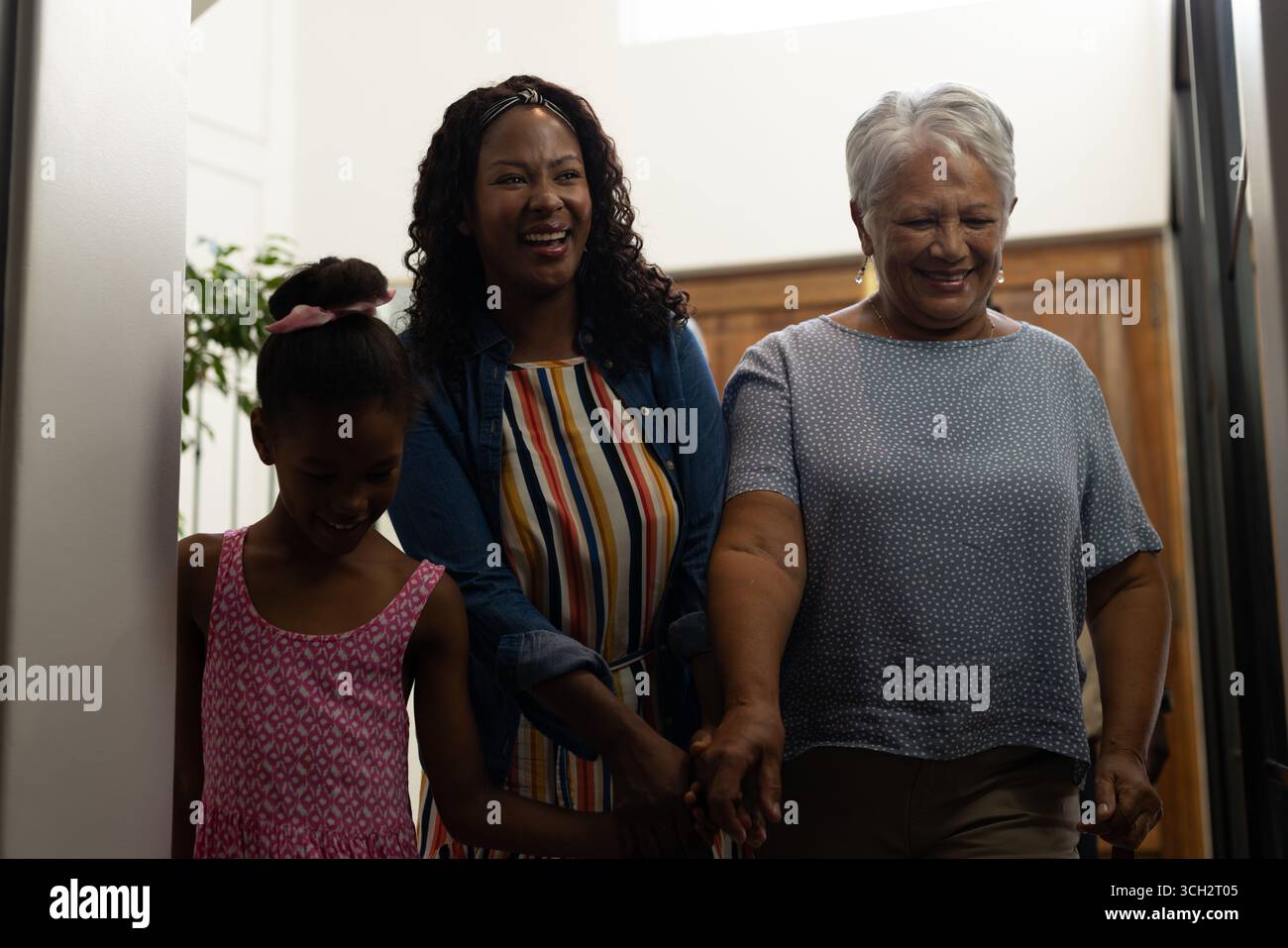 Three generations of women walking together at home, sharing joyful ...