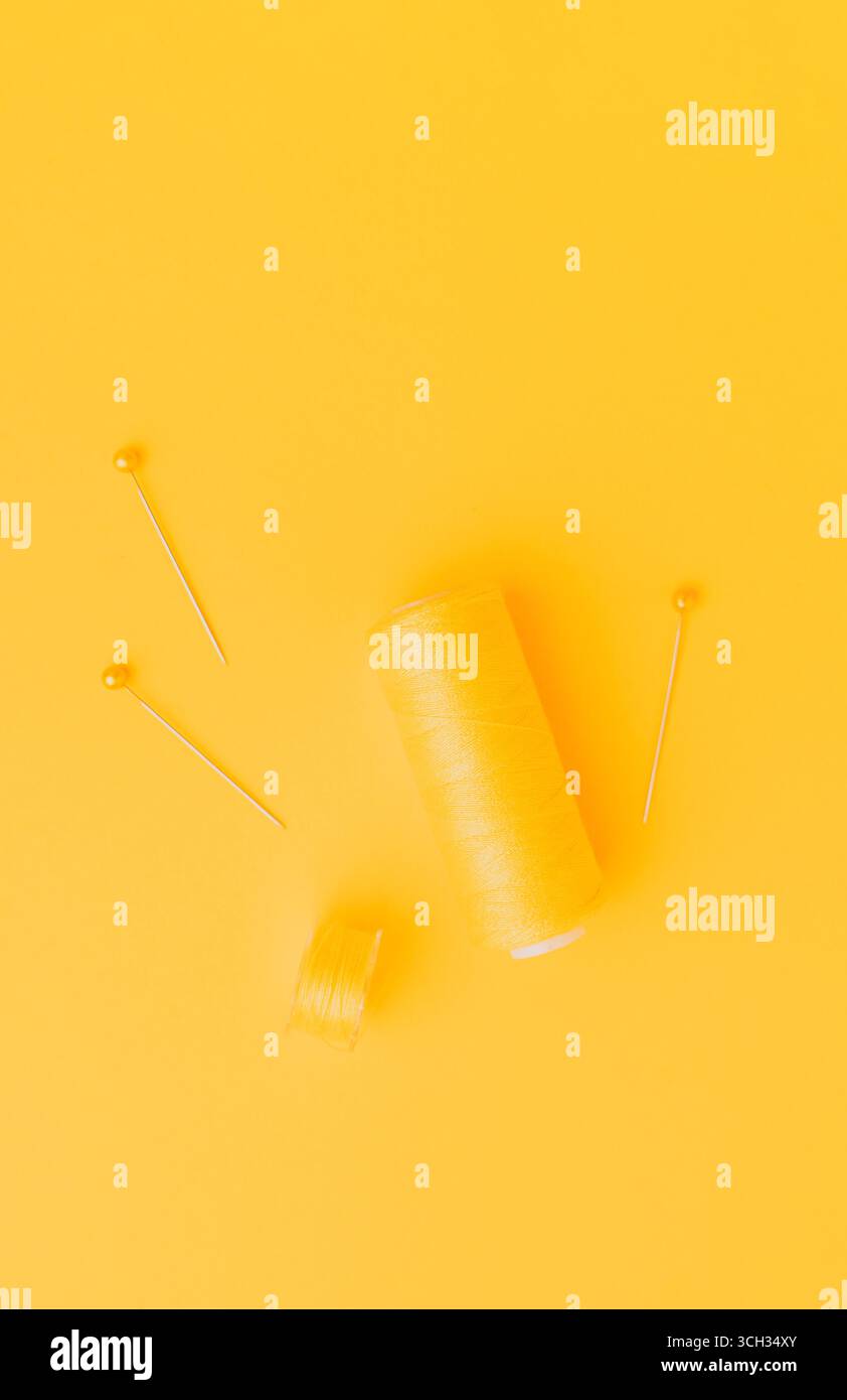 Yellow sewing thread and pins on bright background Stock Photo - Alamy