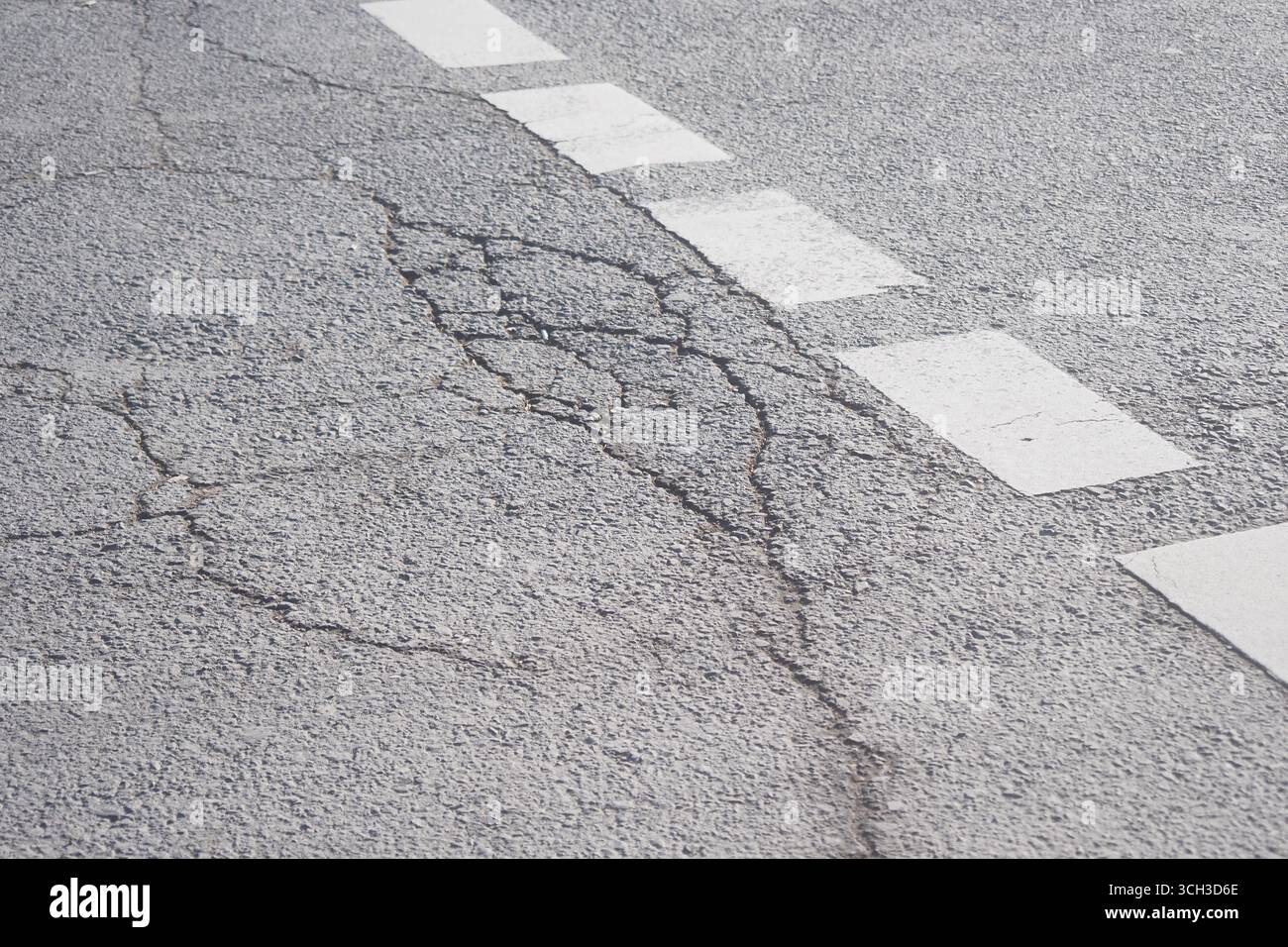 Road surface with cracks and faded lane markings in daylight Stock ...
