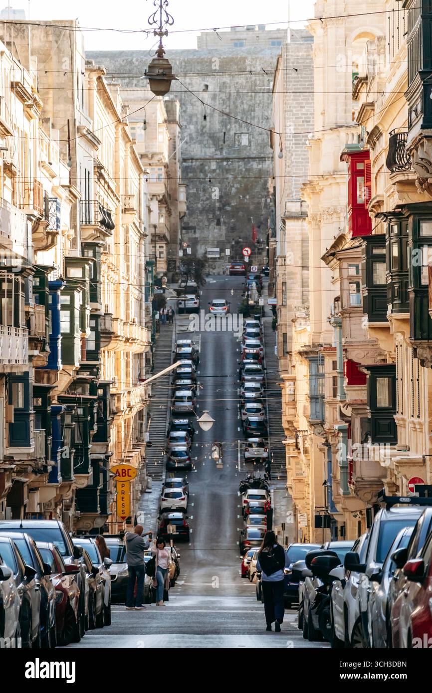Valletta, Malta – April 9, 2025: Sunlit narrow street lined with ...