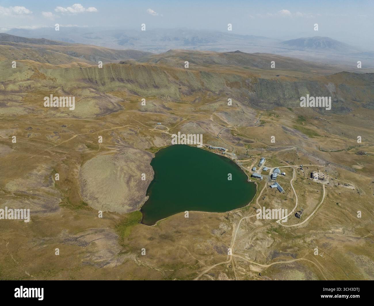 Aerial view of the emerald Lake Kari nestled amidst the rugged, sun ...