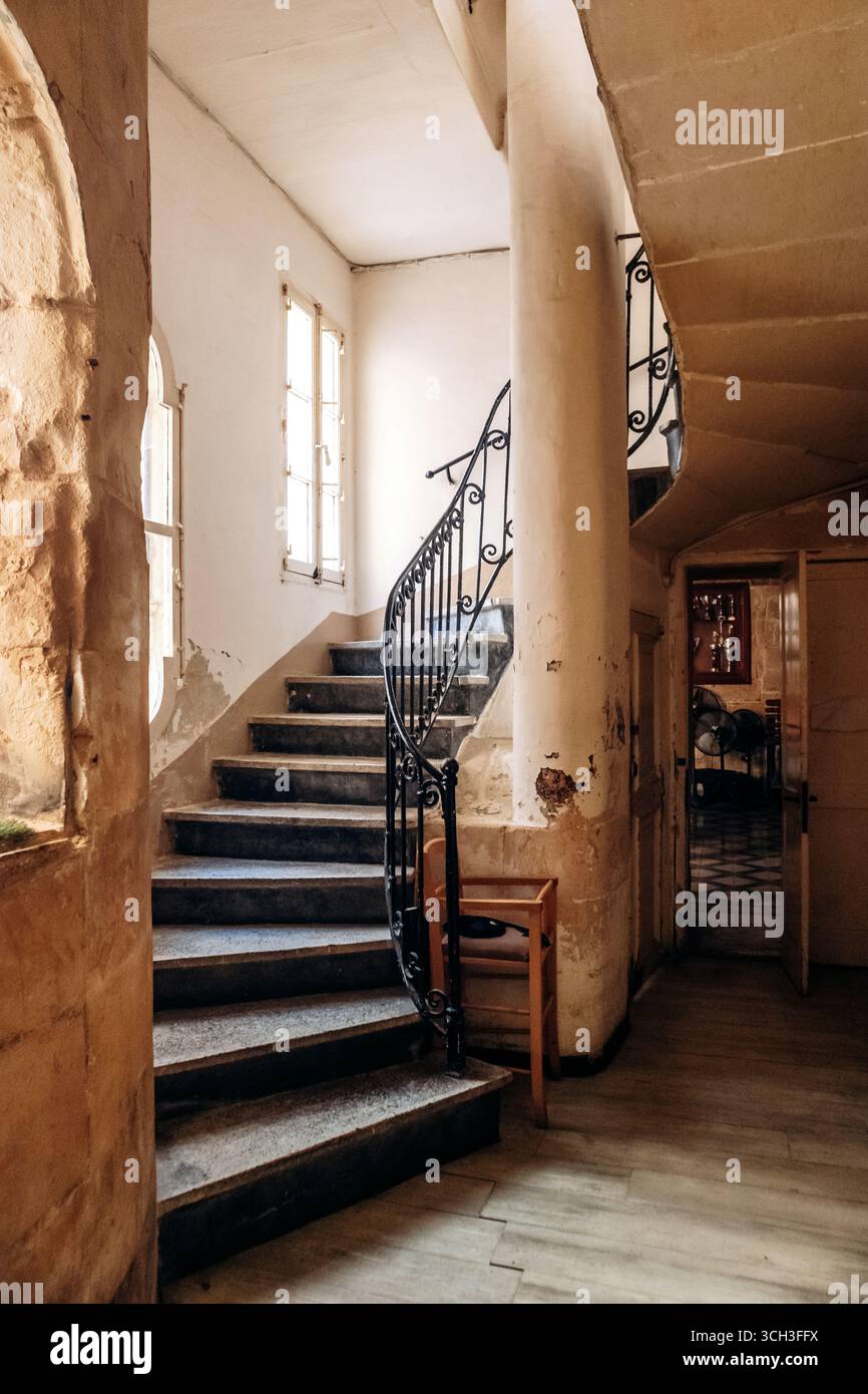 A timeworn stone staircase with ornate black wrought iron railing ...