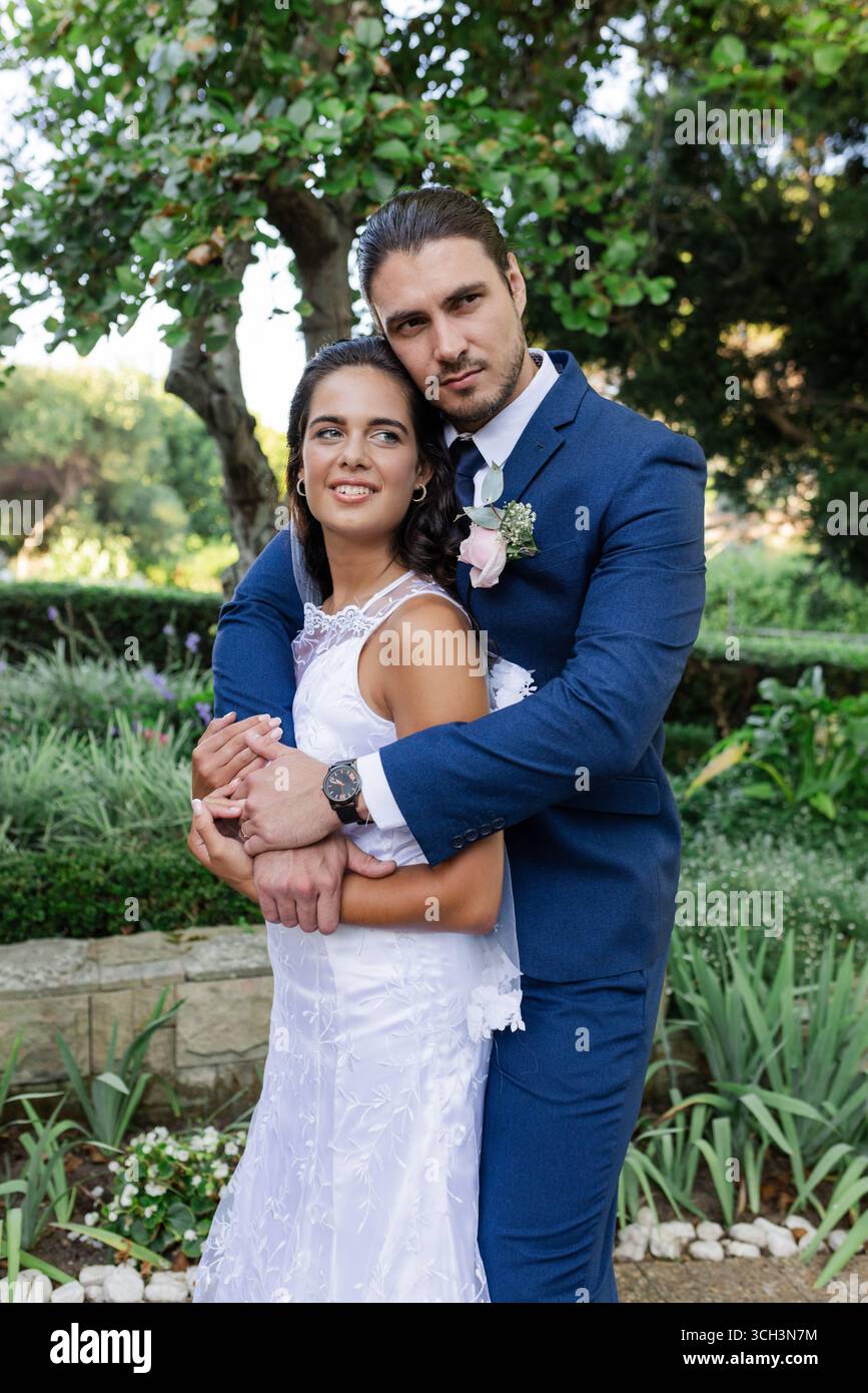 Bride and groom embracing in garden, celebrating love on wedding day ...