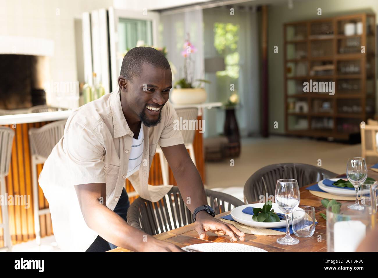 Smiling and leaning across wooden dining table at home with plates ...