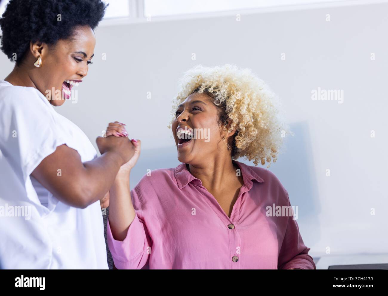 Two friends laughing and celebrating together at home, sharing joyful ...