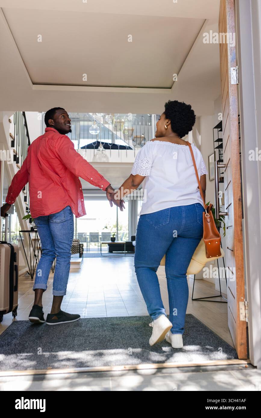 African American Couple entering modern home, holding hands and smiling ...