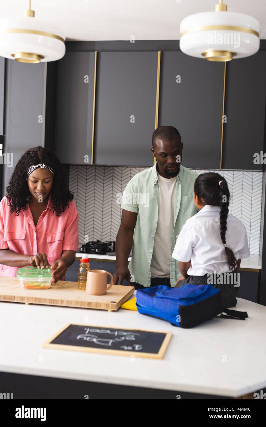 Before school, parents preparing lunch, daughter in school uniform ...