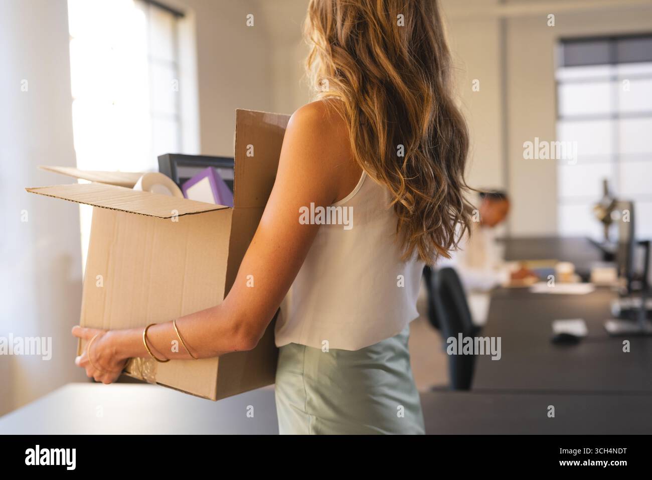 Woman carrying box of office supplies, leaving workplace with ...