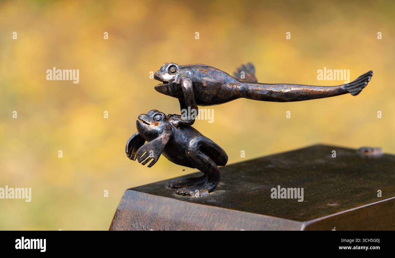 A bronze sculpture showing two frogs, one riding on the back of another ...