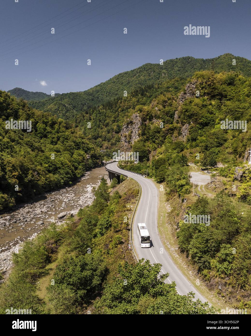 Aerial view of a winding road hugging the rugged riverbank, cutting ...