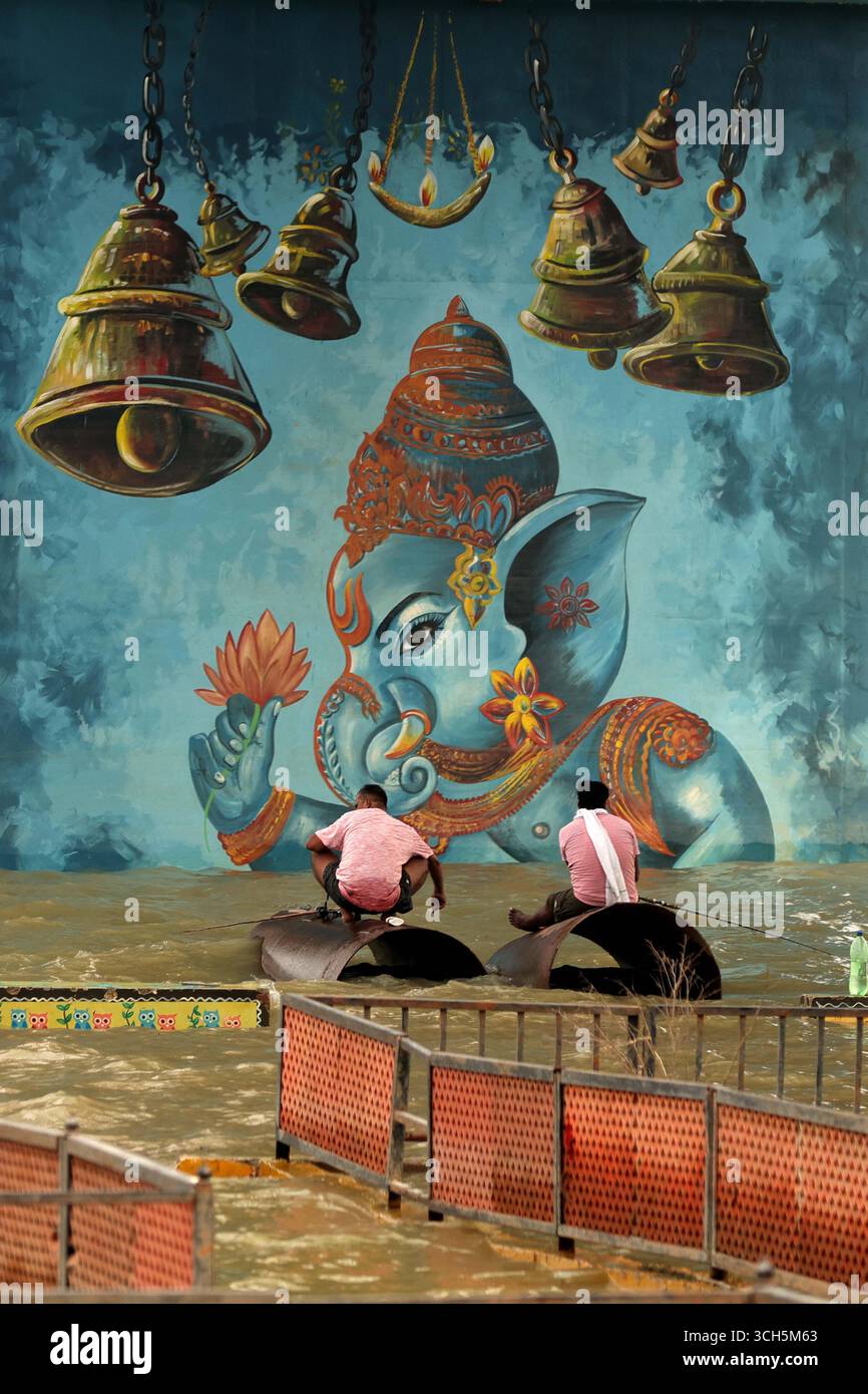 Prayagraj, India. 31 Aug. 2025, People catch fish near a mural of Lord ...