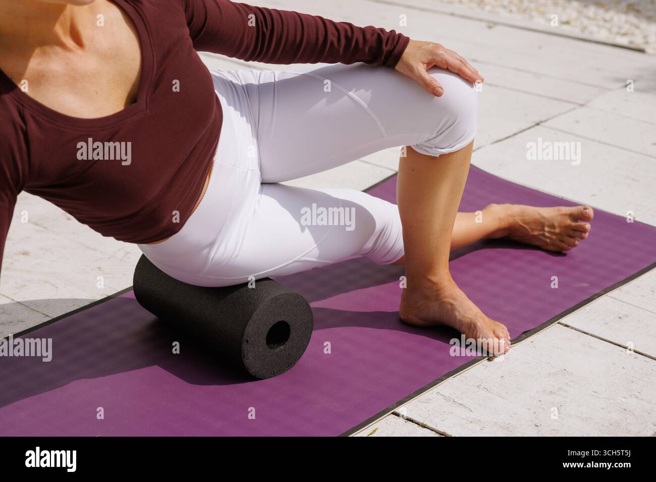 Closeup woman performing glute foam rolling on mat for myofascial ...