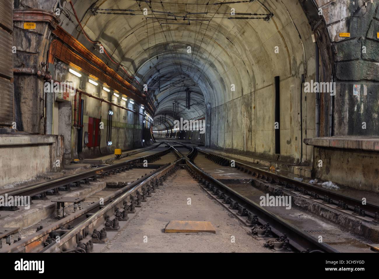 A powerful perspective shot of intersecting train tracks inside a grimy ...