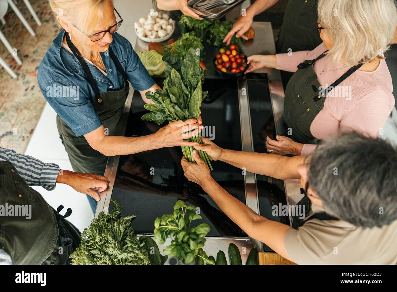 High angle view of senior woman giving spinach to female friend during ...