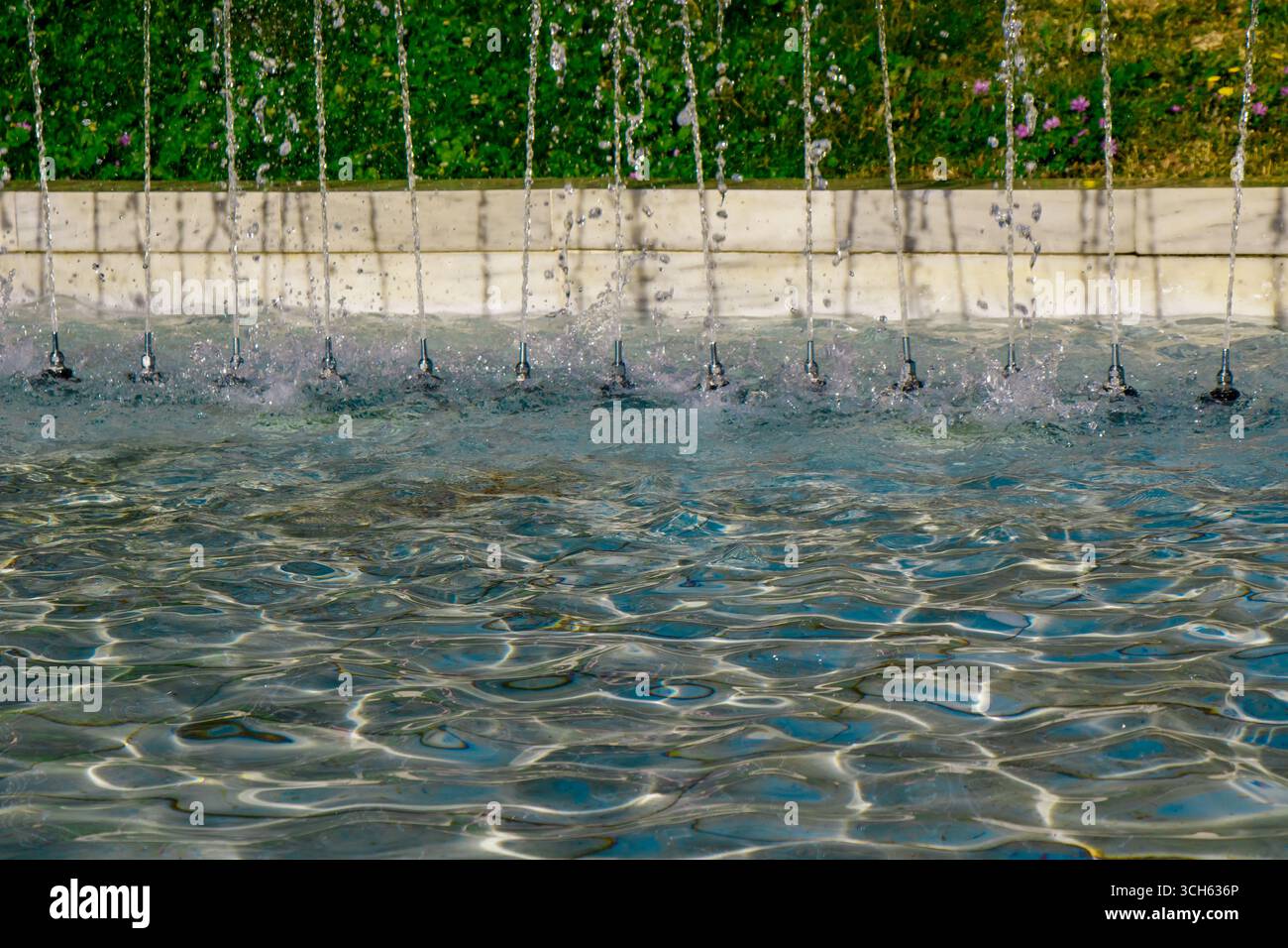 Bright droplets of water burst from multiple fountain nozzles, creating ...