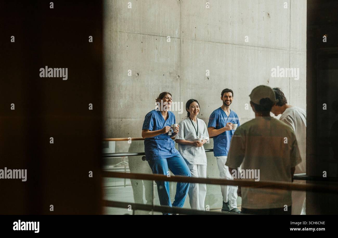 Happy male and female medical professionals enjoying coffee break in ...