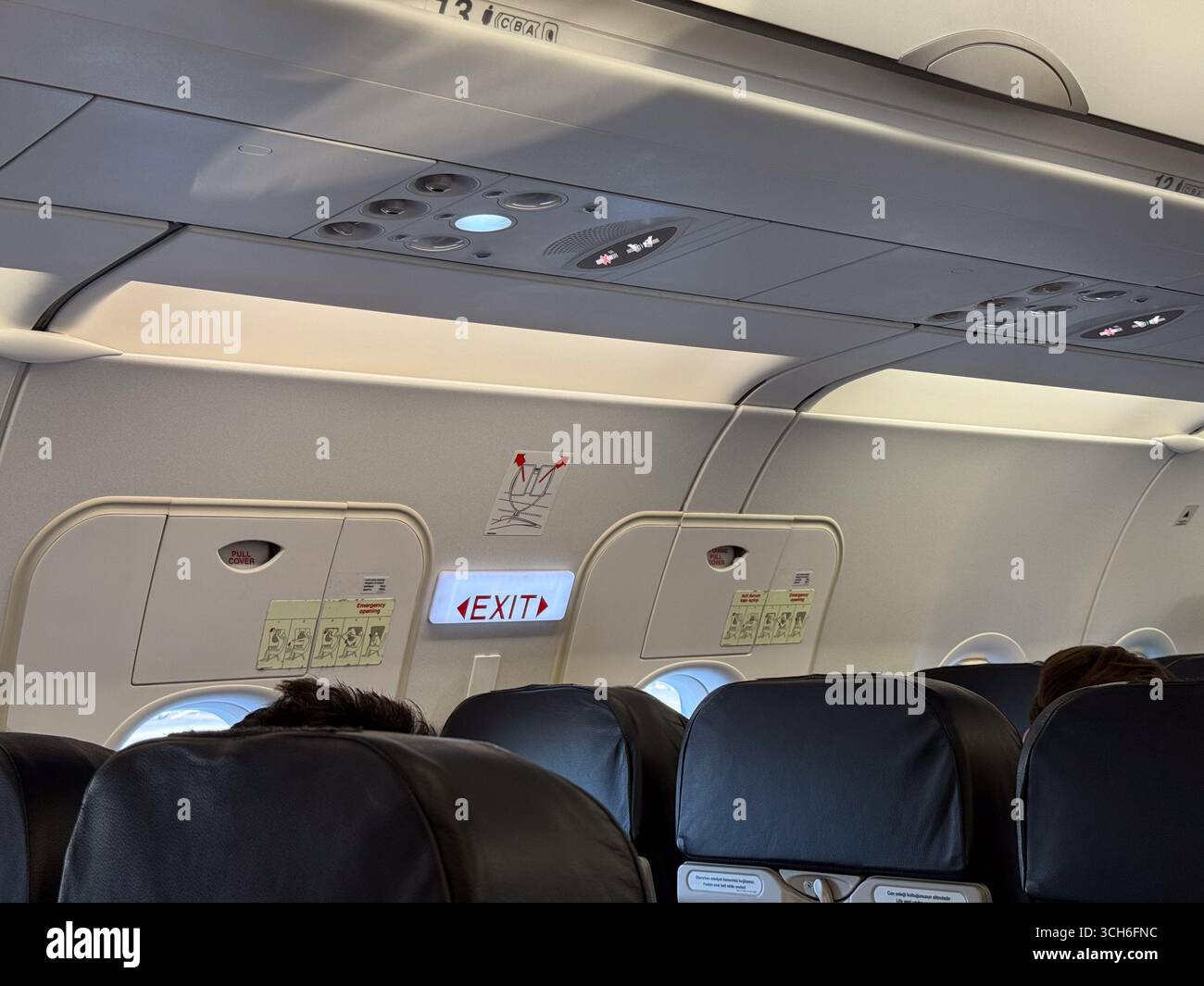 Airplane cabin view with illuminated emergency exit sign and door ...