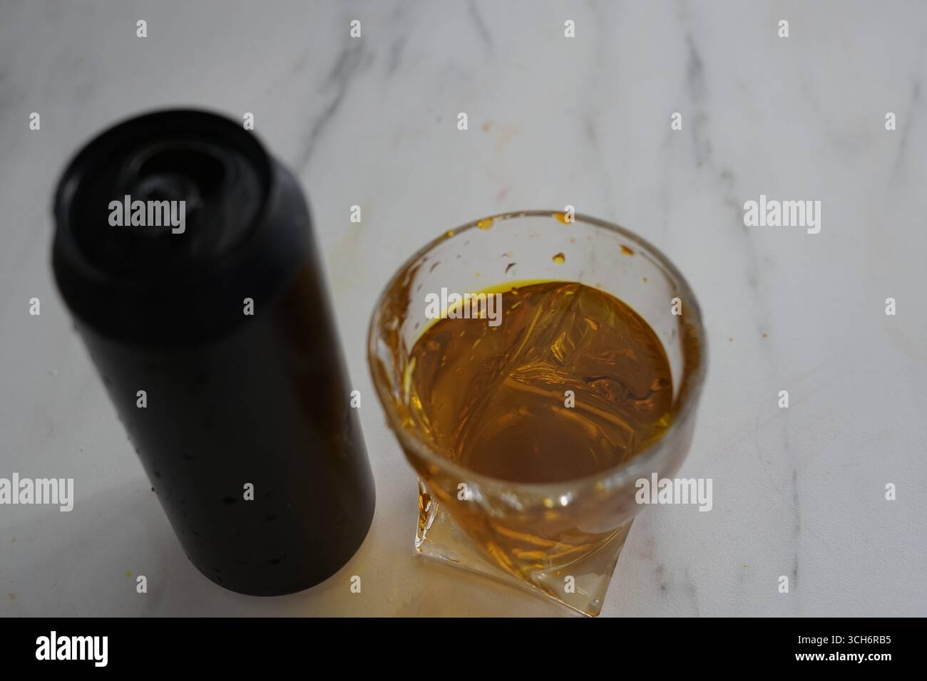 A glass filled with a golden drink is accompanied by a sleek black ...