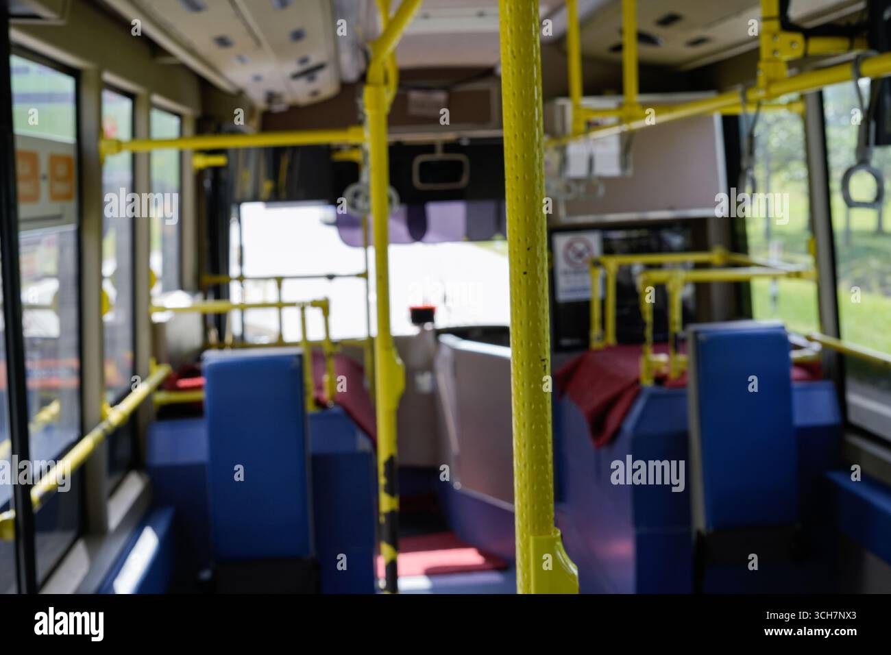 inside a public bus with bright yellow poles, blue seats, and aisle for ...