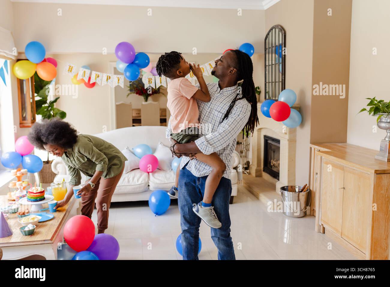 At party, African American father holding son at birthday party, mother ...