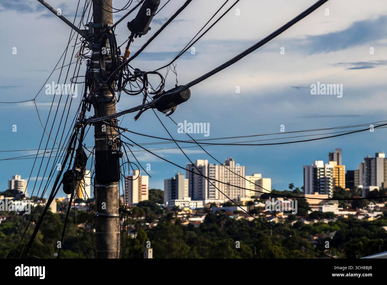 Tangled wires on a utility pole against a cityscape. Illustrates urban ...