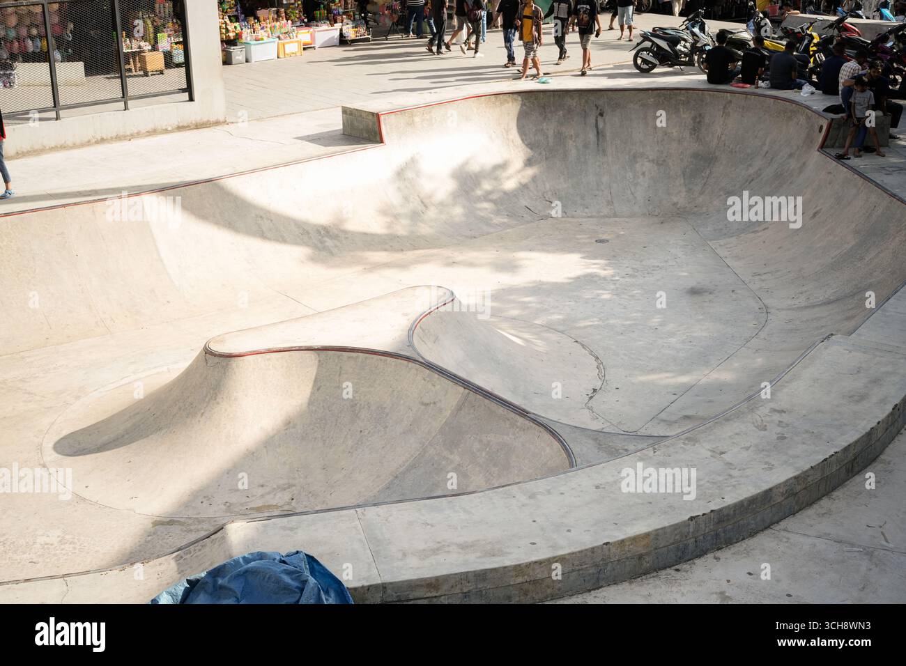 modern concrete skatepark with curved ramps under sunny outdoor setting ...