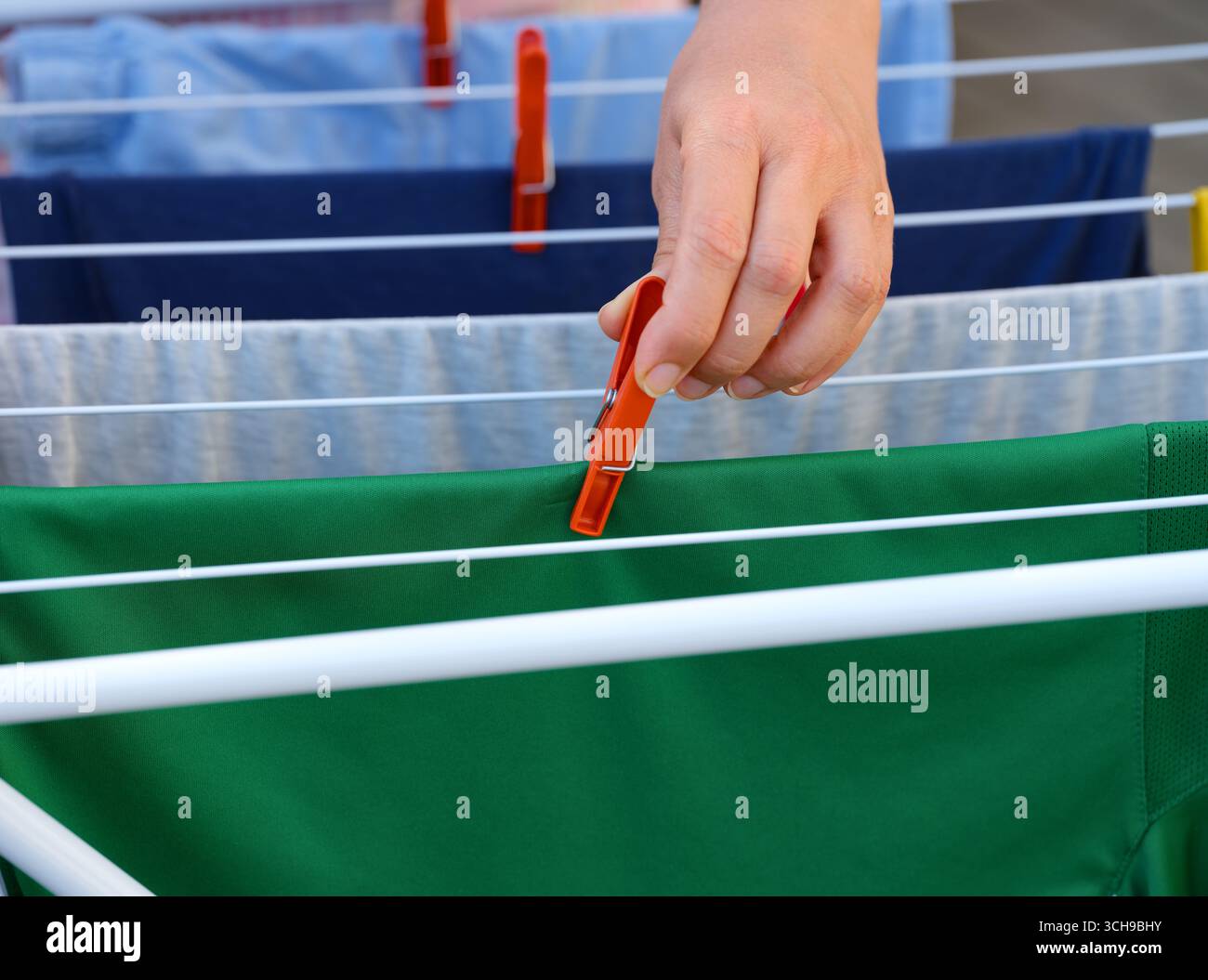 A woman using a clothespin to hang up laundry to dry. Close-up Stock ...