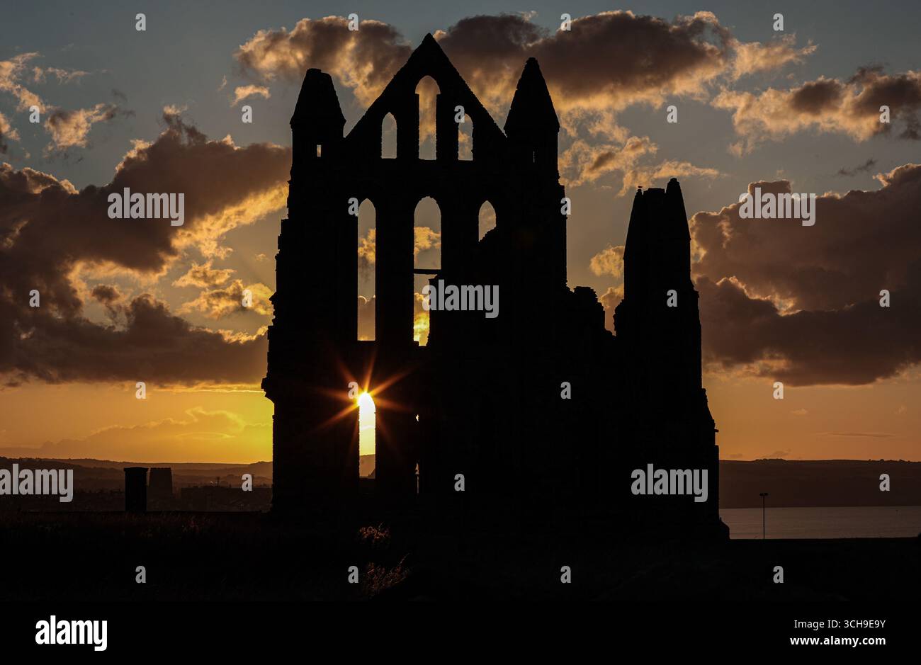 The sun sets behind Whitby Abbey at Whitby , Whitby, United Kingdom ...