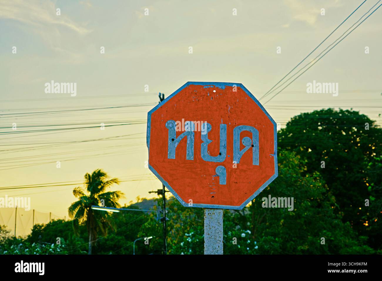on old rusty stop sign at sunset in thailand written in thai language ...