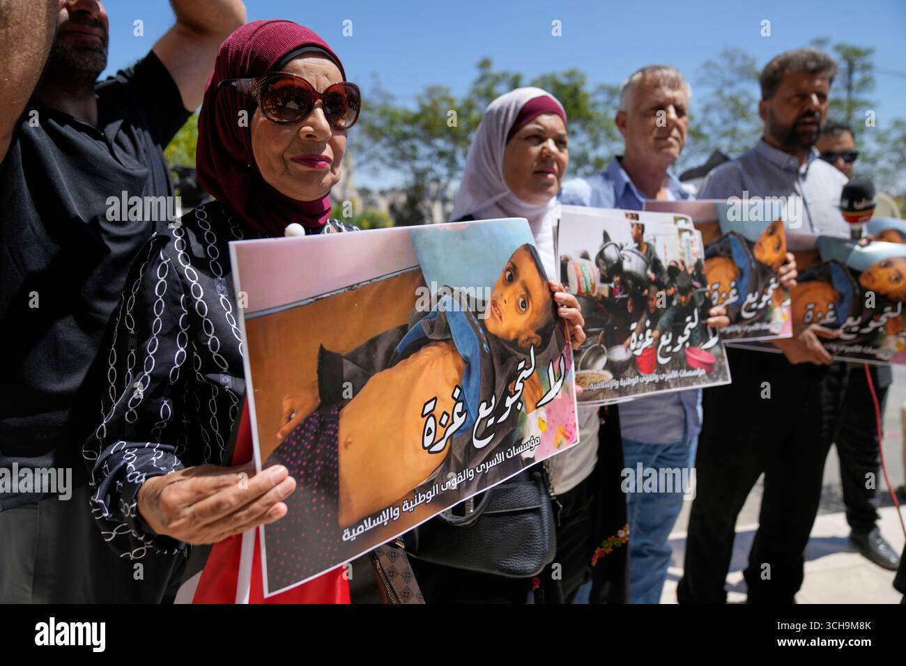 Palestinian protesters carry posters reading "No to the starvation of ...