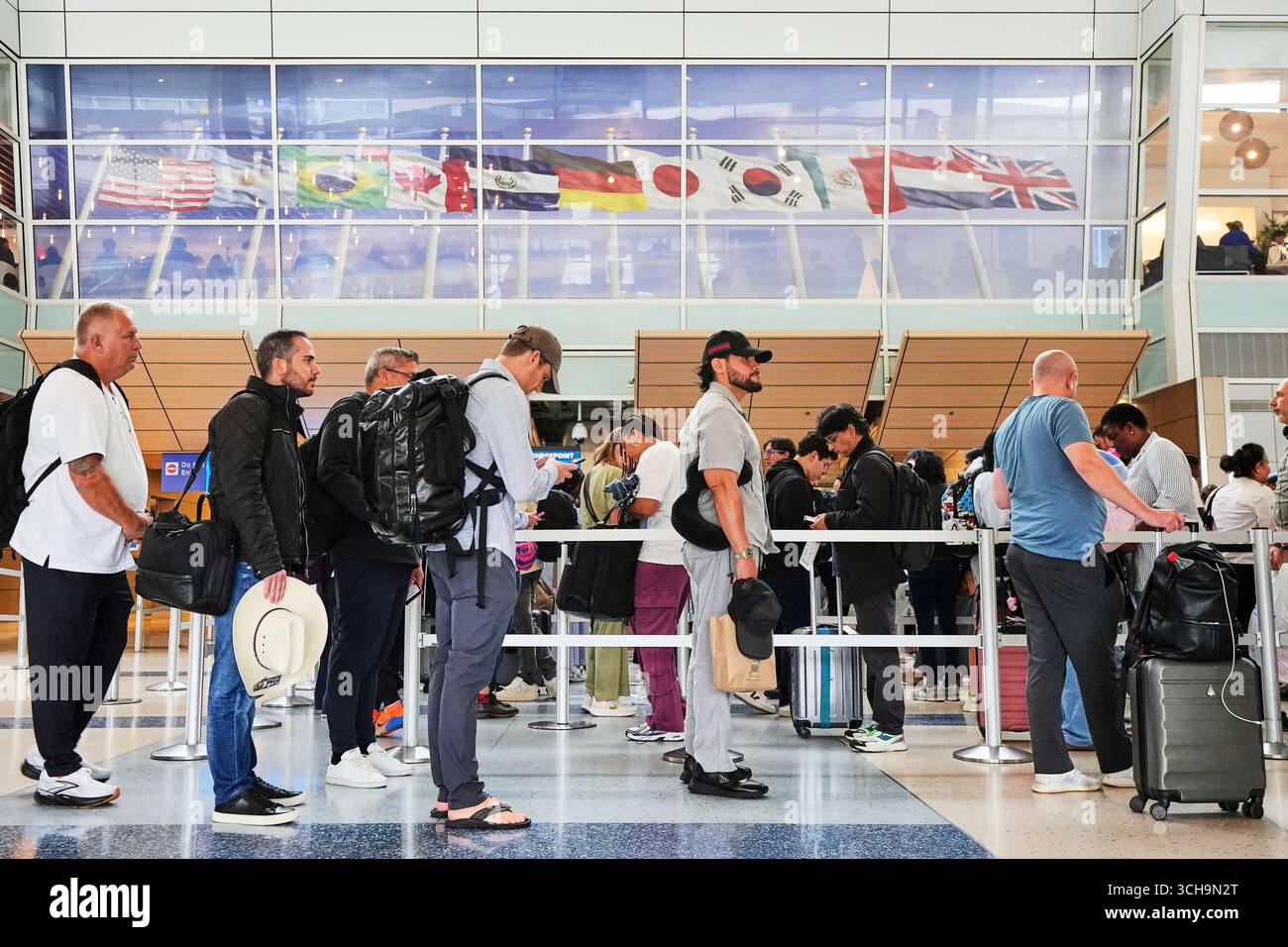 Travelers Stand in line at a security checkpoint before boarding their ...