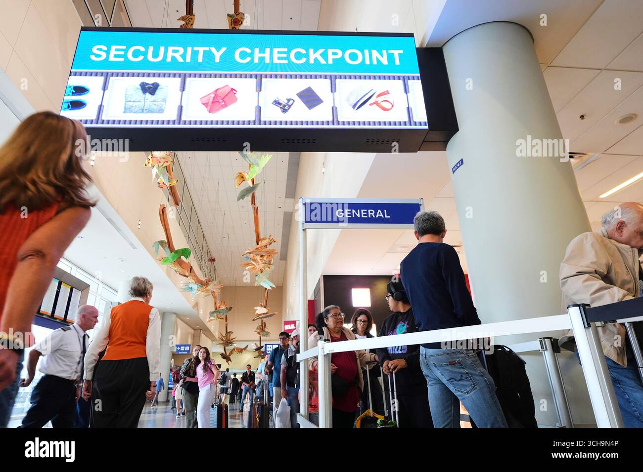 Travelers make their way to and past a security checkpoint at Terminal ...