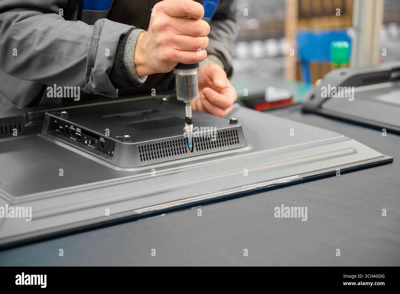 Worker assembles television housing in a television assembly plant ...