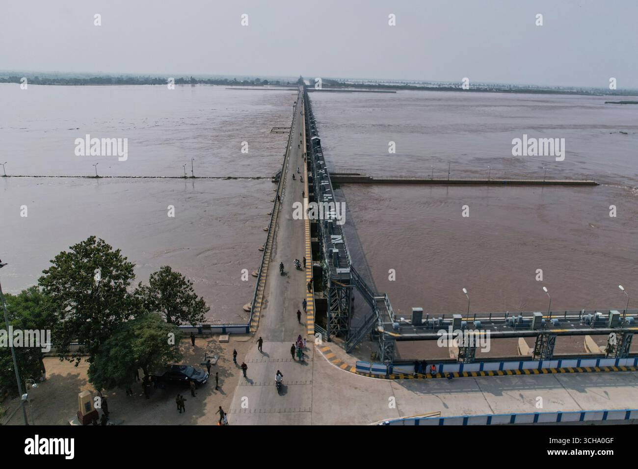 Motorcyclists drive through Trimmu Barrage on the River Chenab, which ...