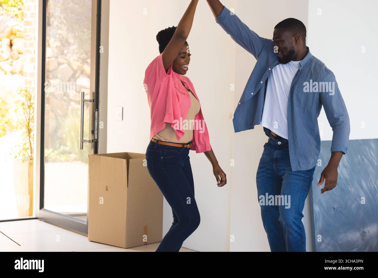 African American couple dancing joyfully in new home, celebrating ...